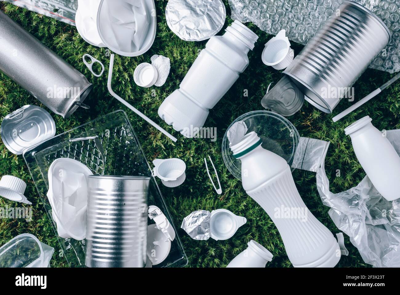 Plastic waste, food packaging, trash collection on green moss ...