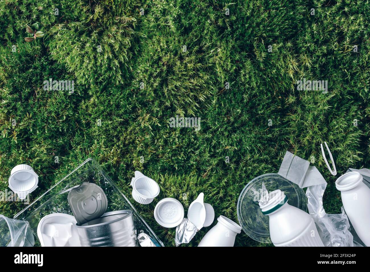 Food plastic packaging, trash on green moss background after picnic in ...