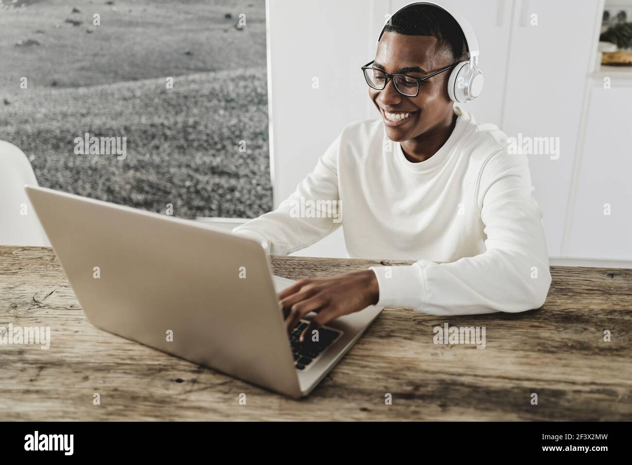 Young african man using laptop computer while wearing headphones at ...