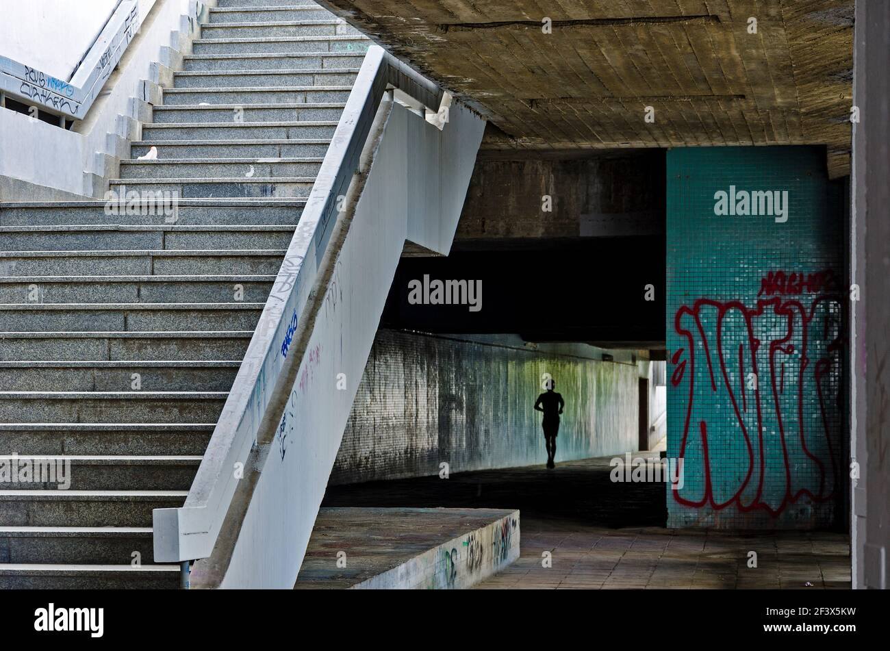 Silhouette of the runner in a dark void urban subway with dirty ...