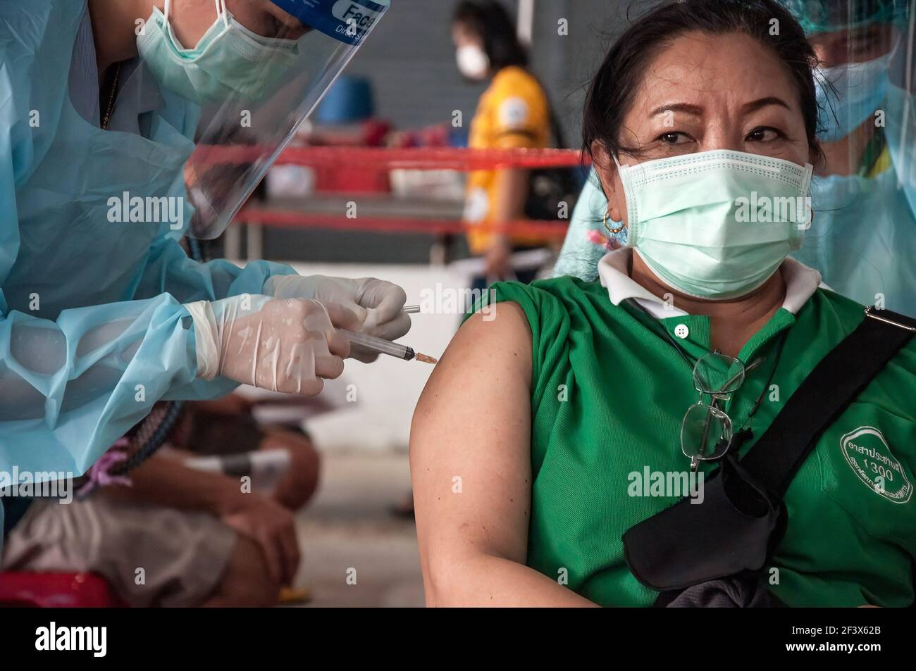 Bangkok, Thailand. 18th Mar, 2021. A woman wearing a face mask receives ...
