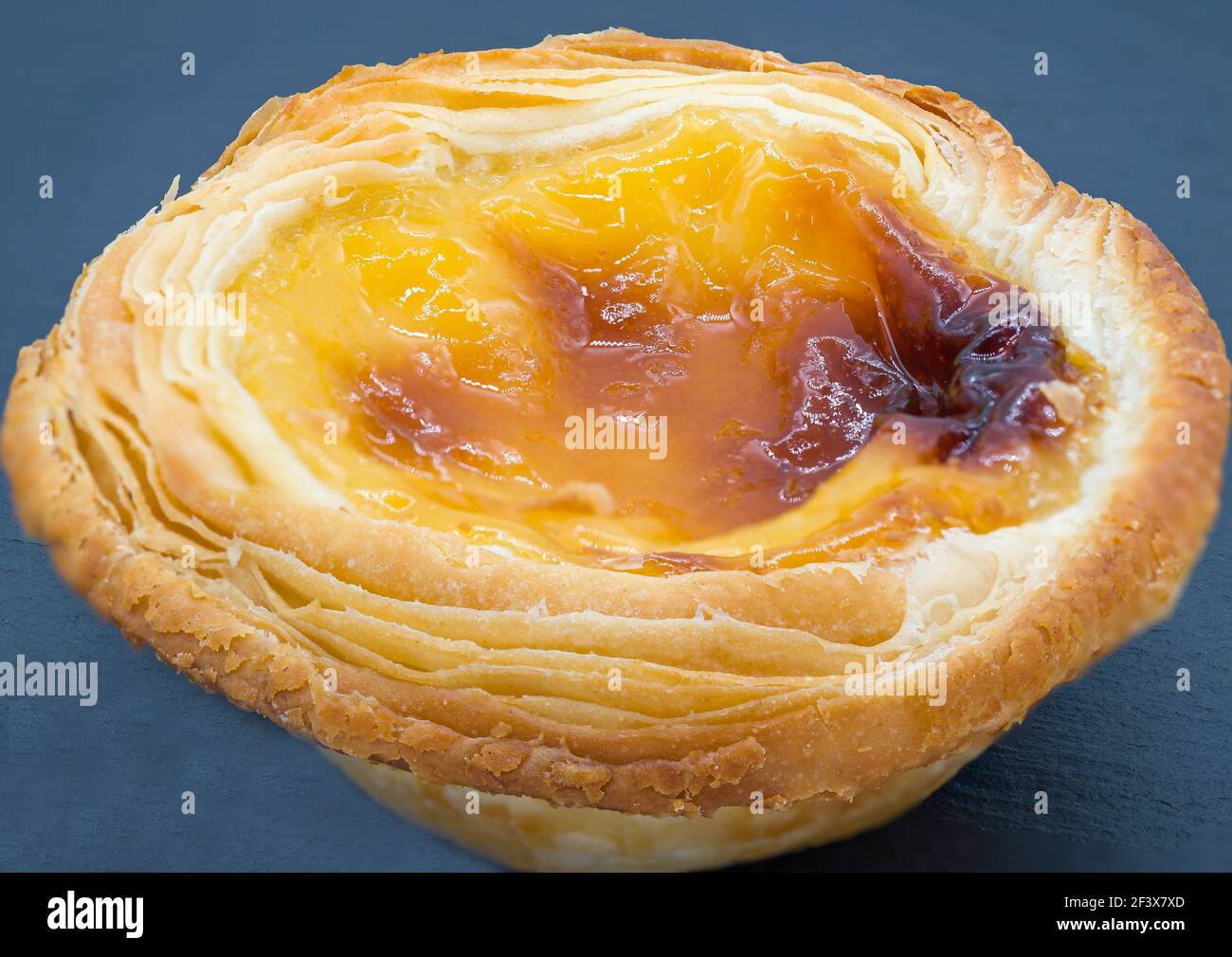 One small custard tart on a dark grey background Stock Photo - Alamy