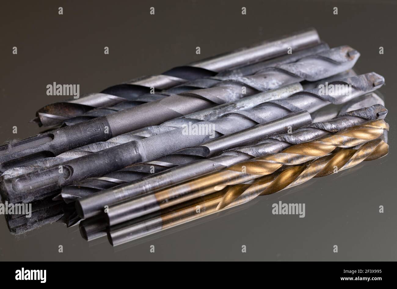 A group of drills, dirty after use, on a mirrored background. Tools for ...