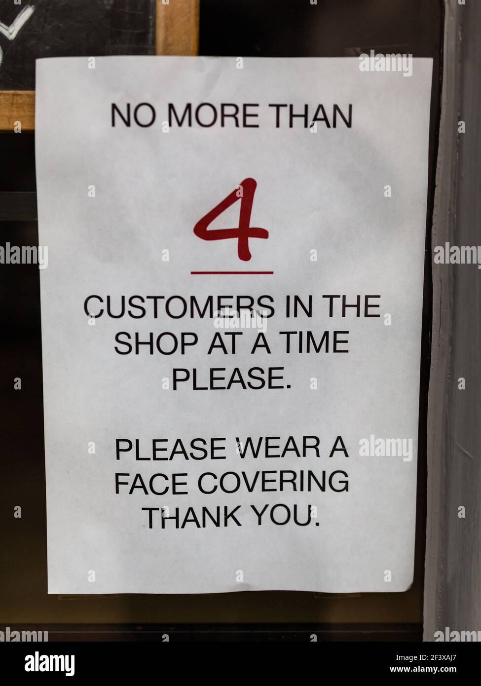 A window sign in a small store informing the public that only 4 ...