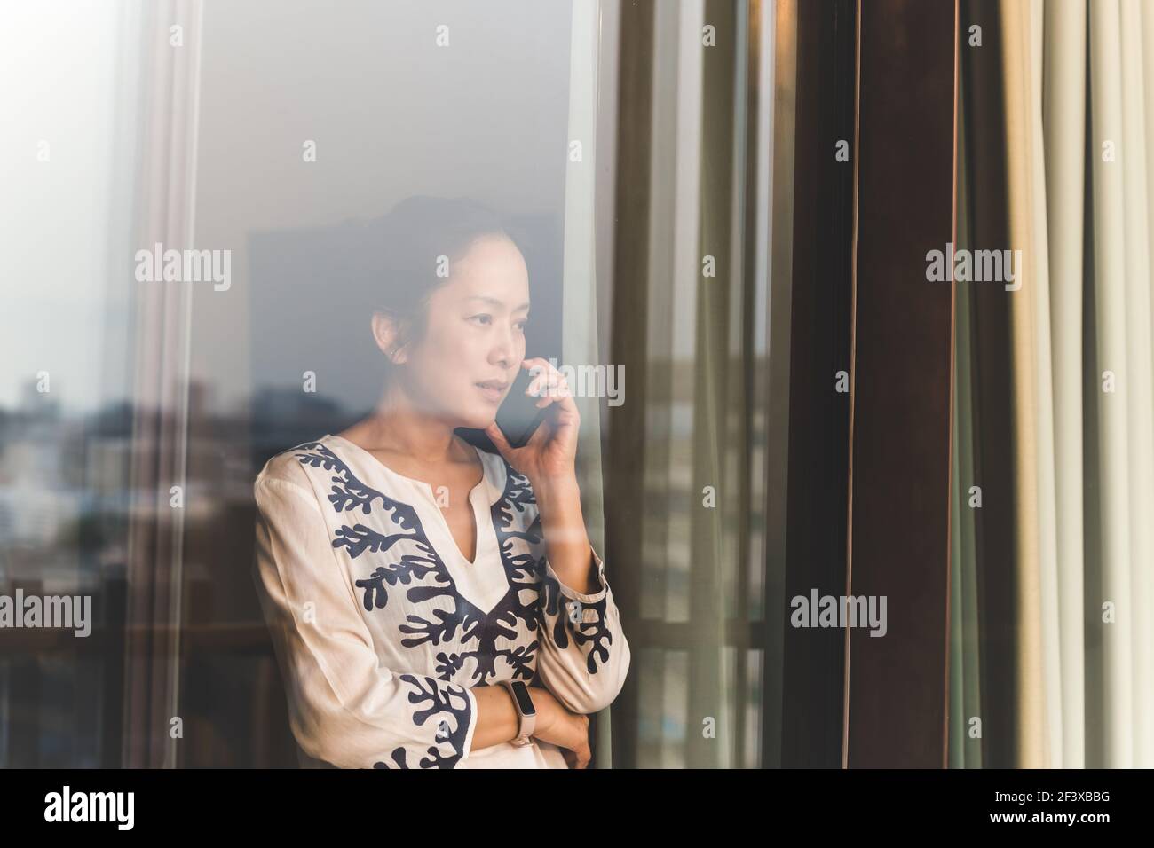Shot through window of woman talking on cell phone in hotel room Stock ...