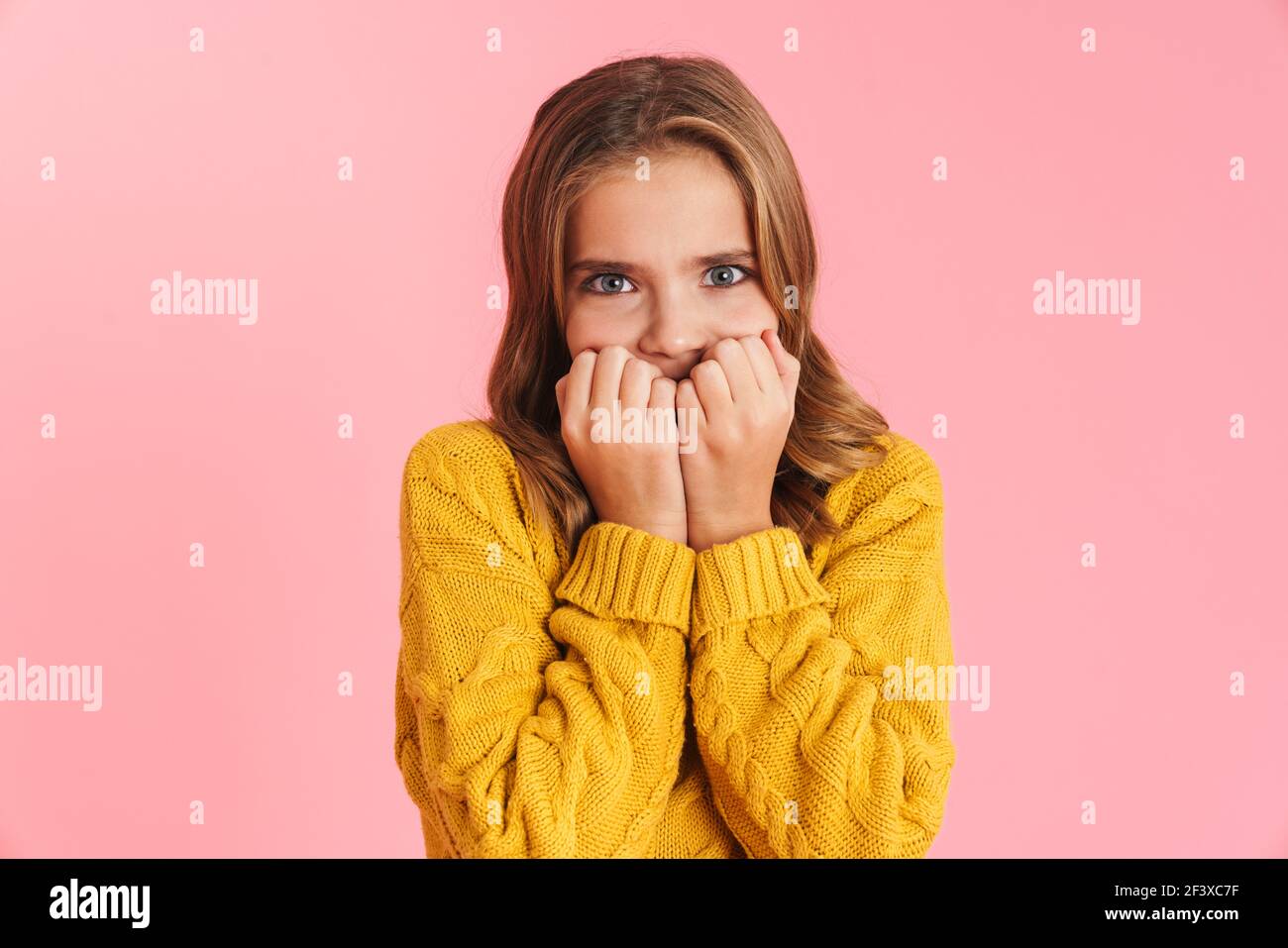 Scared beautiful blonde girl covering her face and looking at camera ...