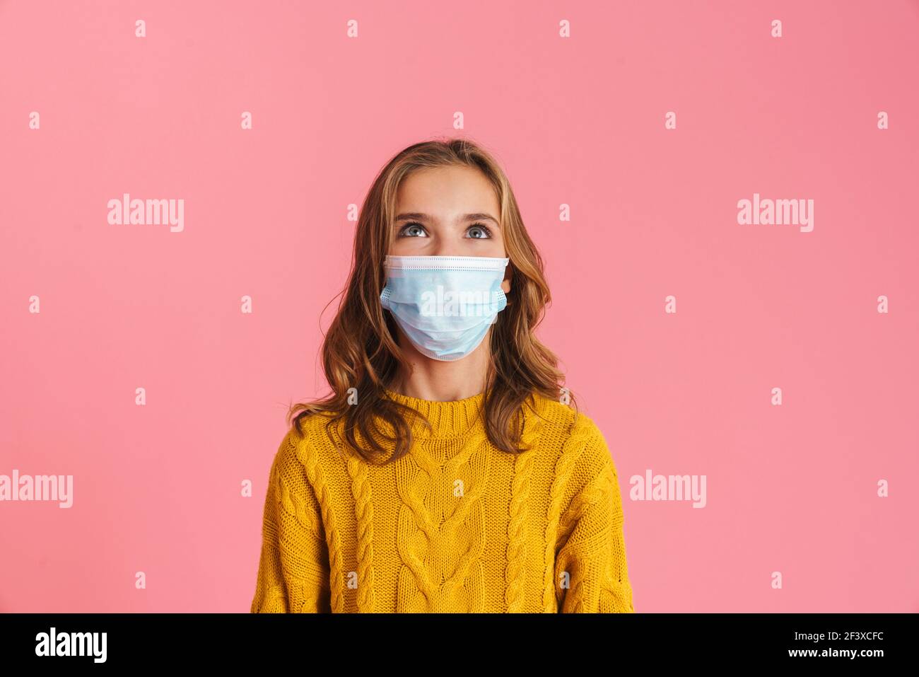 Happy beautiful girl in face mask posing and looking upward isolated ...