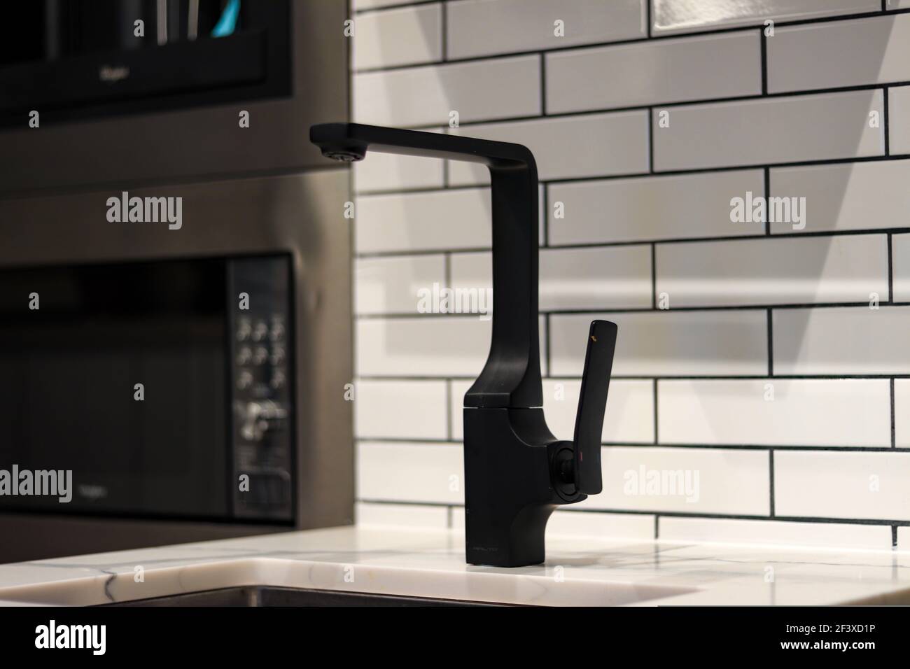 A modern black sink tap on the background of a ceramic tile wall Stock ...