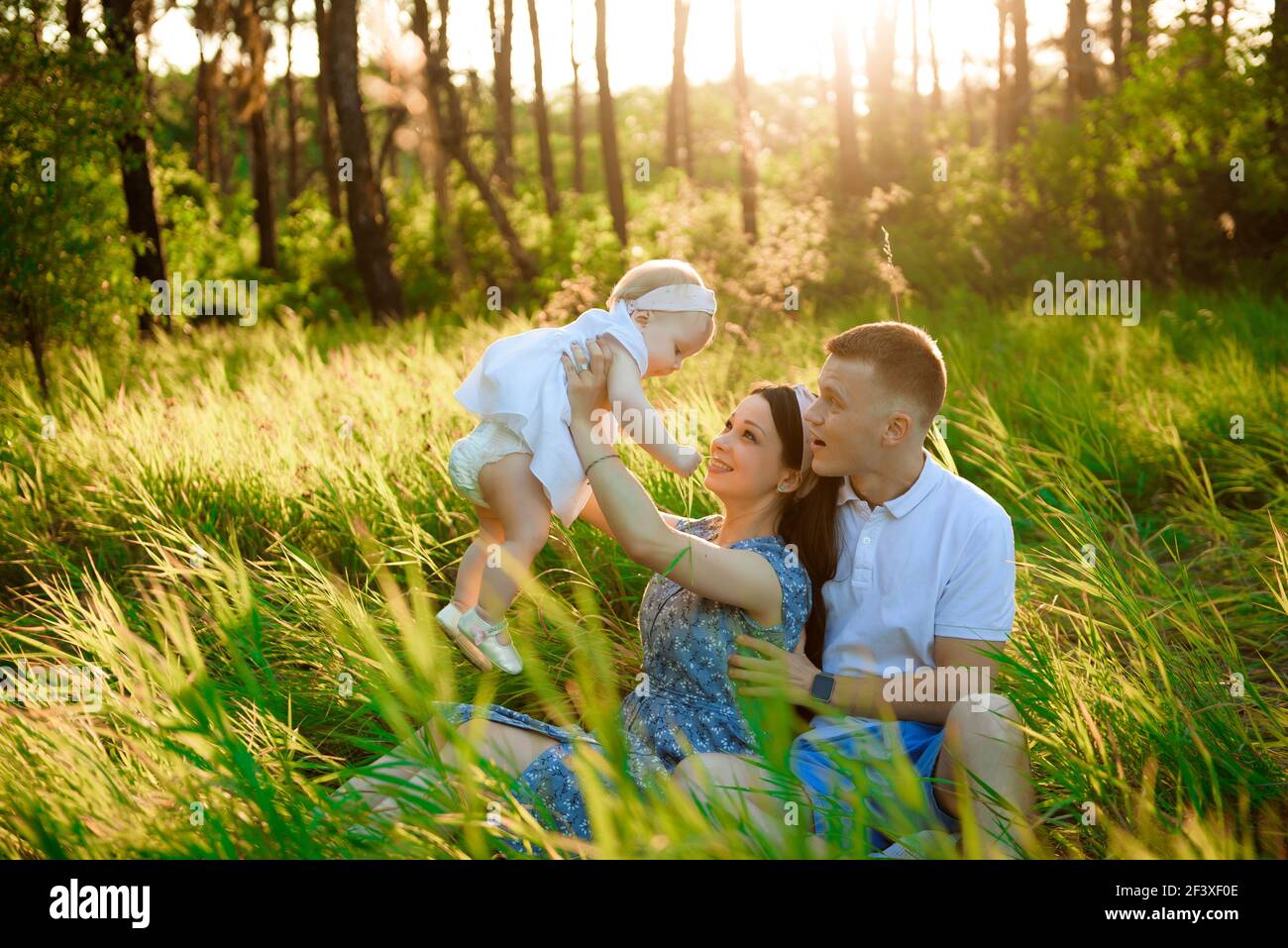 Happy family dad, mom playing in the fresh air on the field watching ...