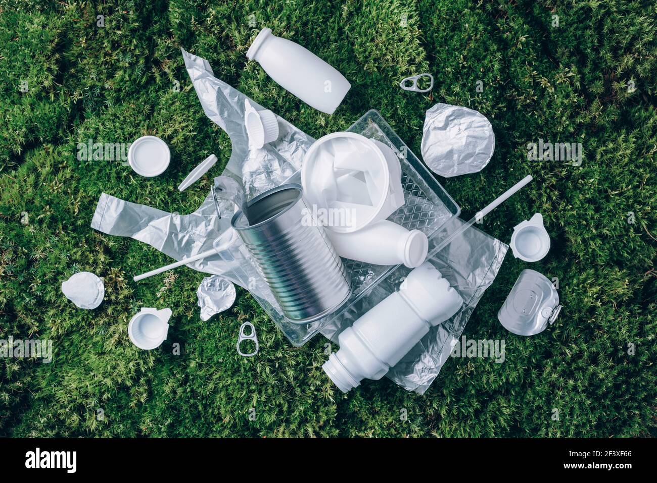 Plastic waste, food packaging, trash collection on green moss ...