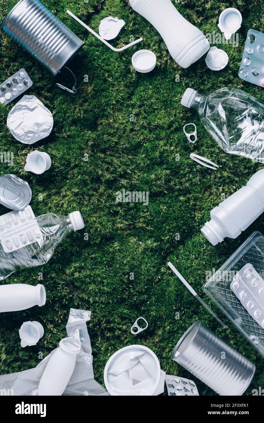 Plastic waste, food packaging, trash collection on green moss ...