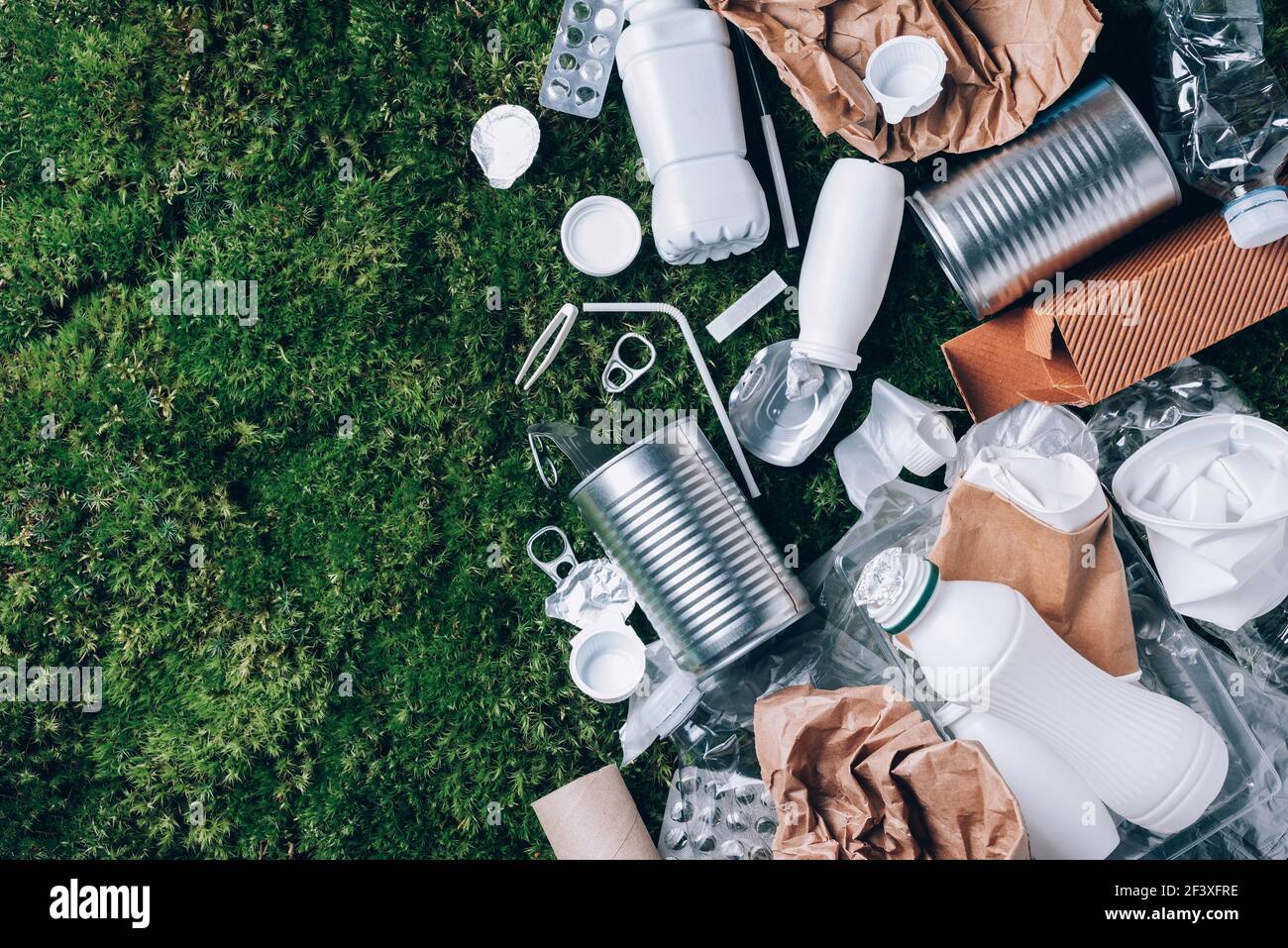 Plastic waste, food packaging, trash collection on green moss ...