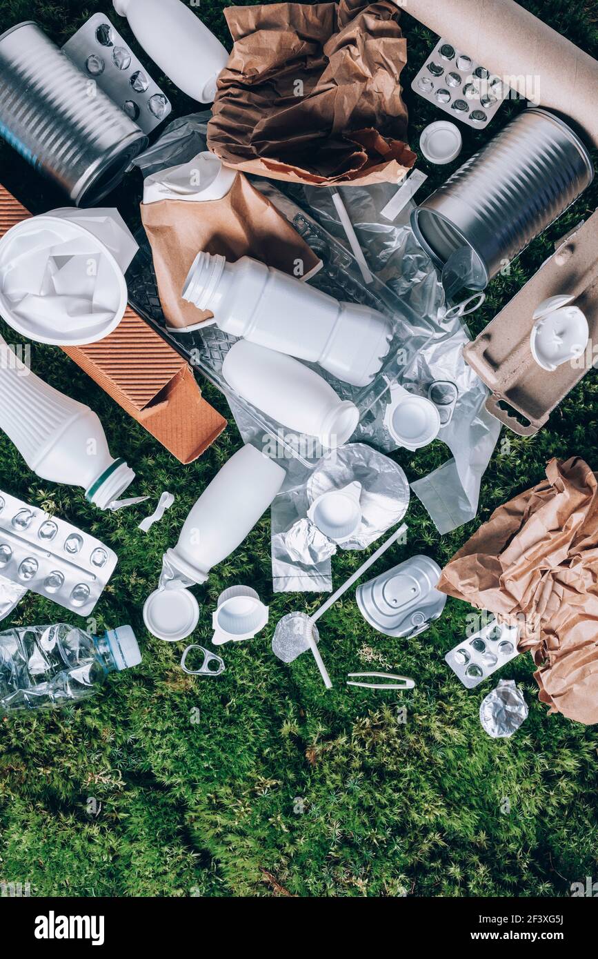 Plastic waste, food packaging, trash collection on green moss ...