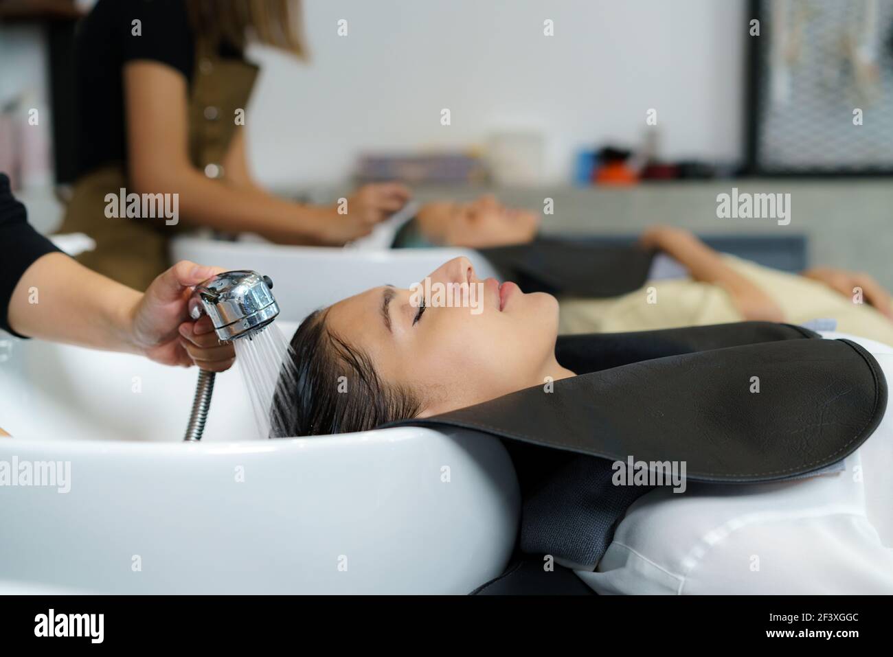Hairdresser is applying shampoo and massaging hair of a customer. Woman ...