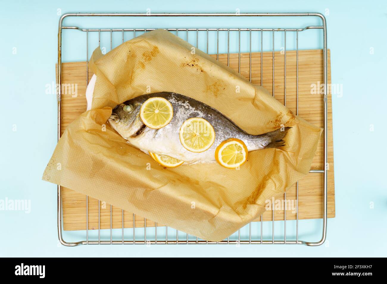 Flat lay baked or grilled dorado fish with lemon cooked home on blue ...