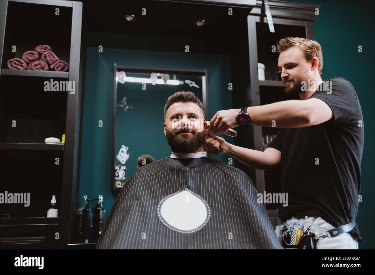 Hairdresser cutting hair of client man with clipper in barbershop Stock ...
