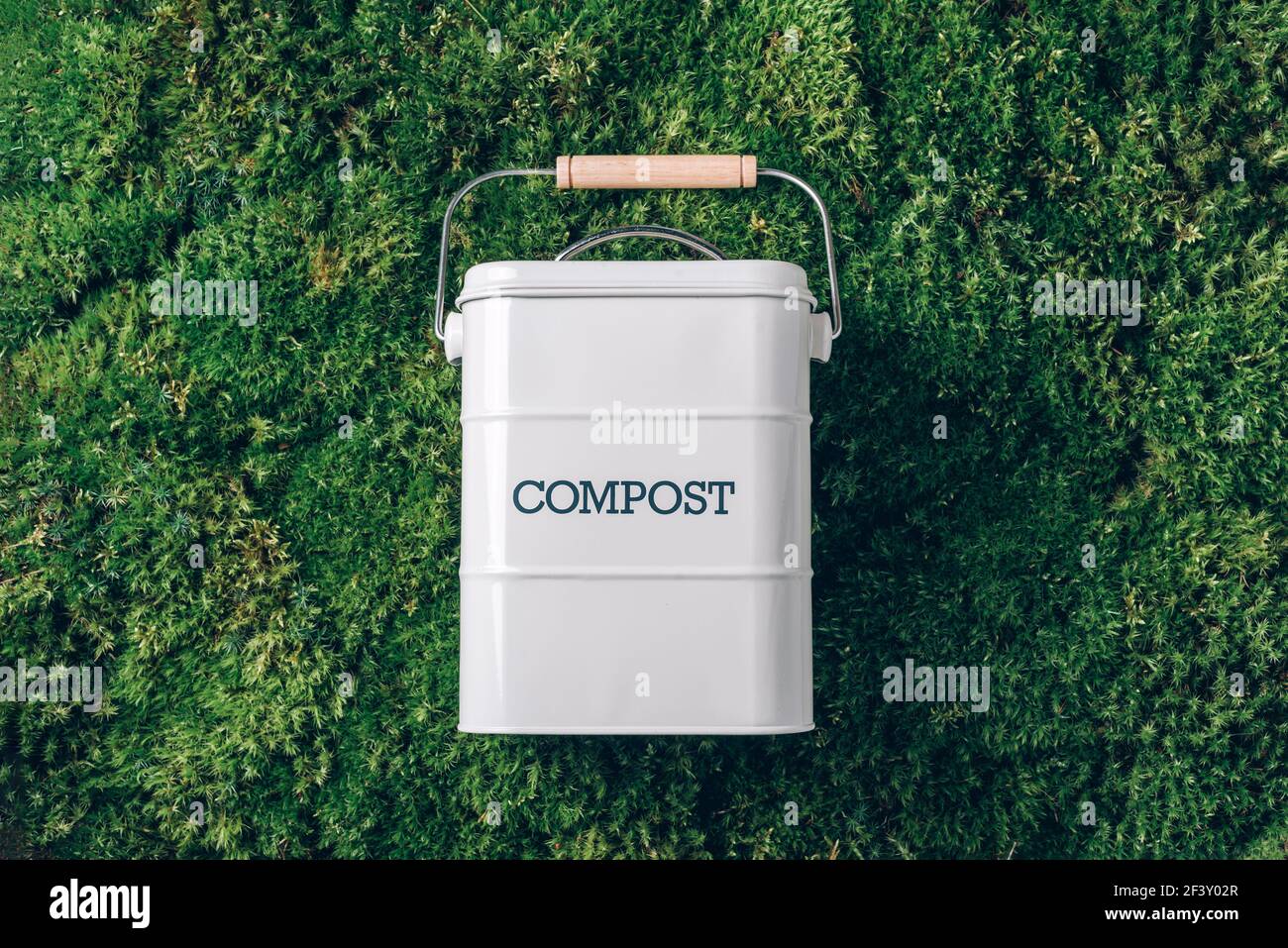 Trash bin for composting with leftover from kitchen on green grass ...