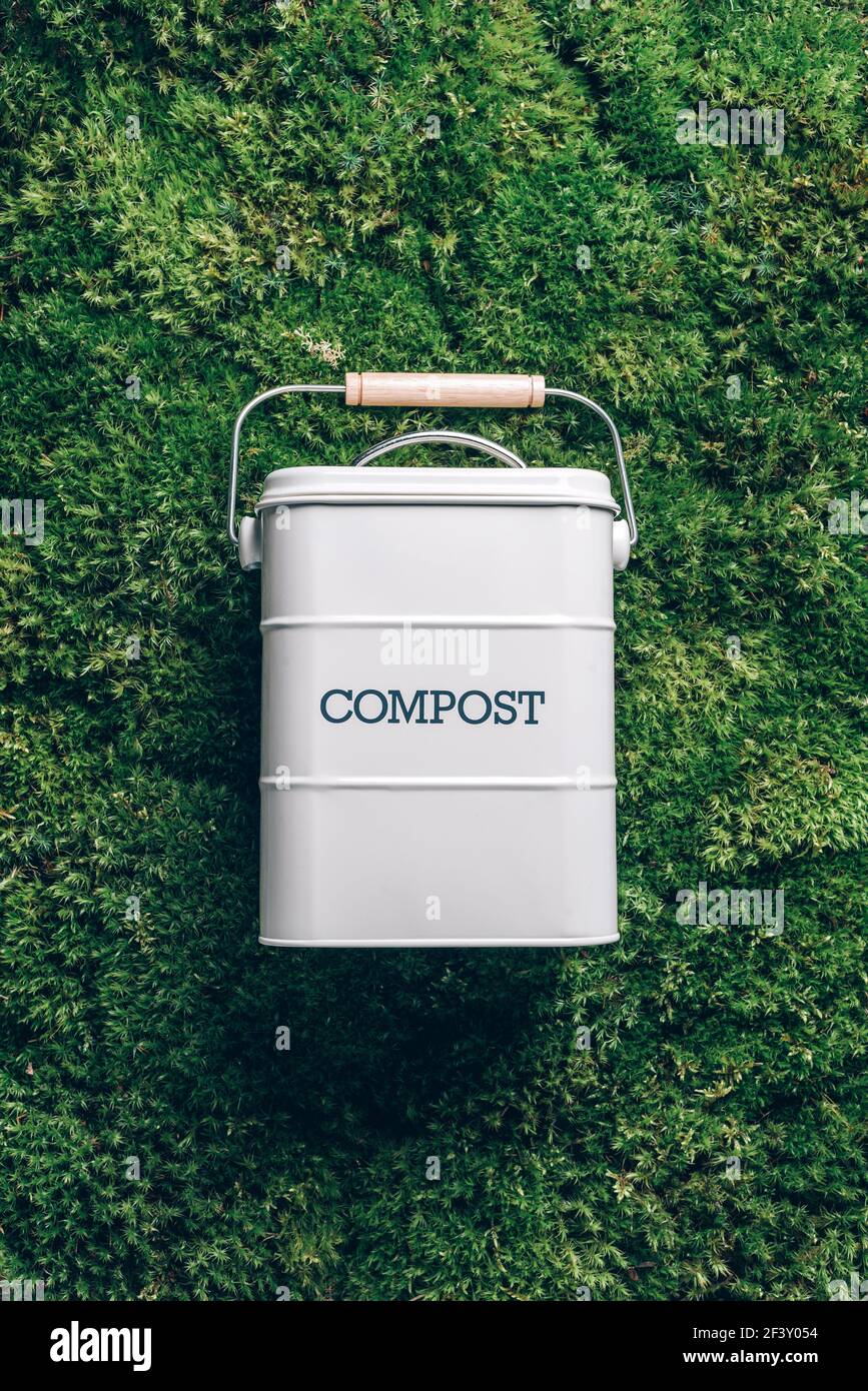 Trash bin for composting with leftover from kitchen on green grass ...