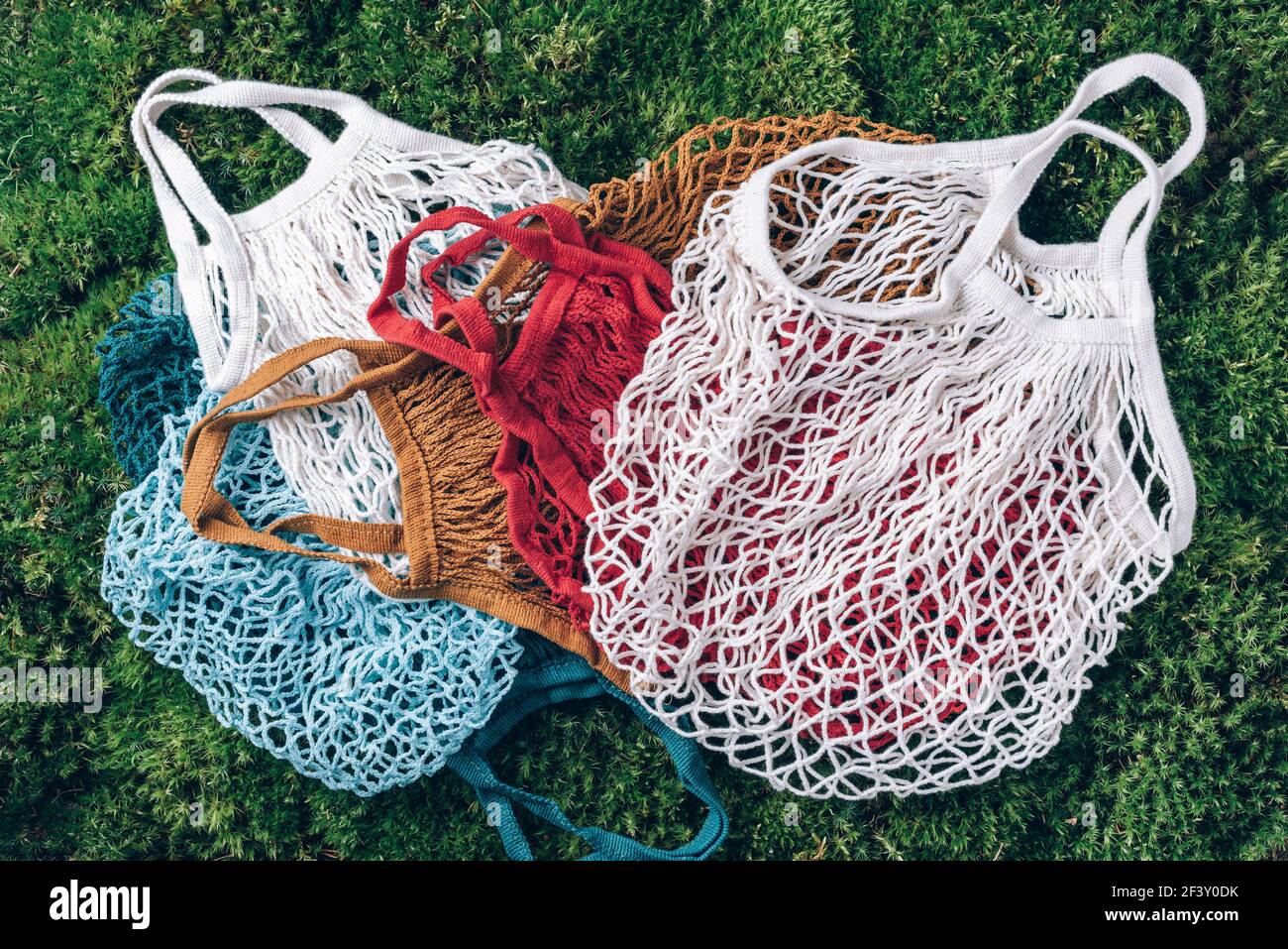 Colorful reusable net bags or mesh shoppers on green grass, moss ...