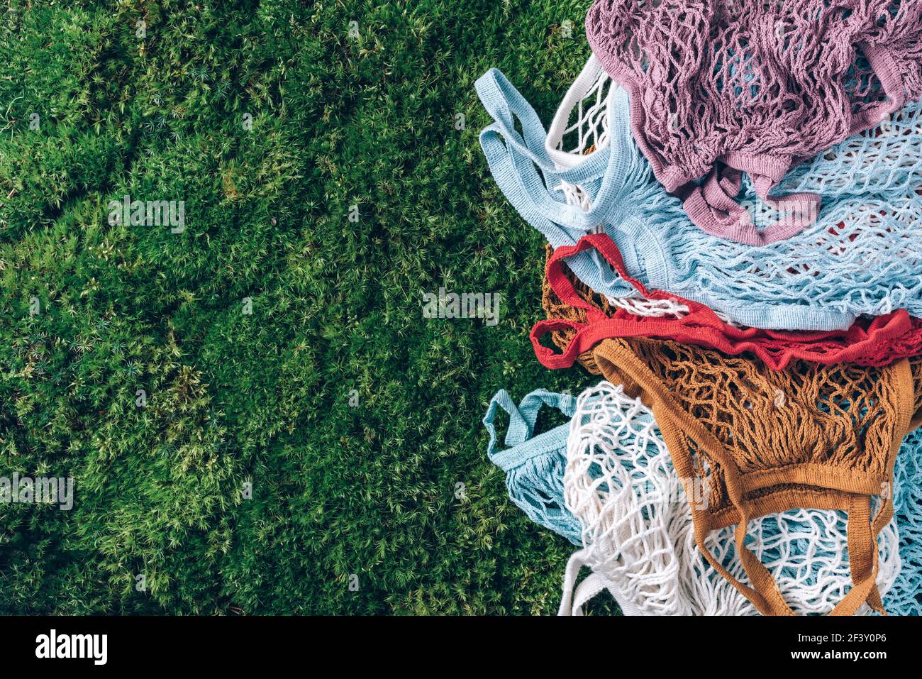 Colorful reusable net bags or mesh shoppers on green grass, moss ...