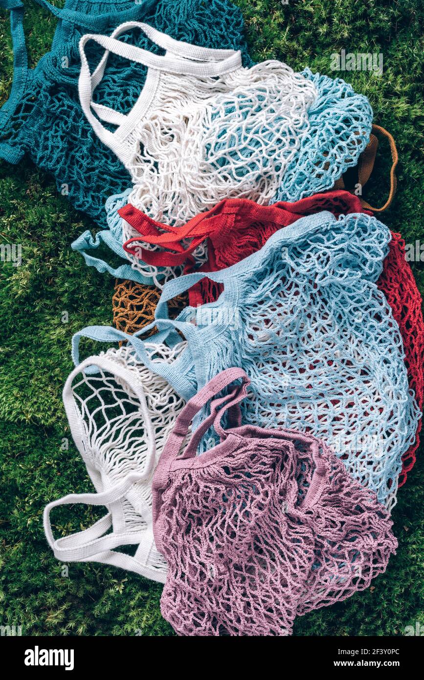 Colorful reusable net bags or mesh shoppers on green grass, moss ...