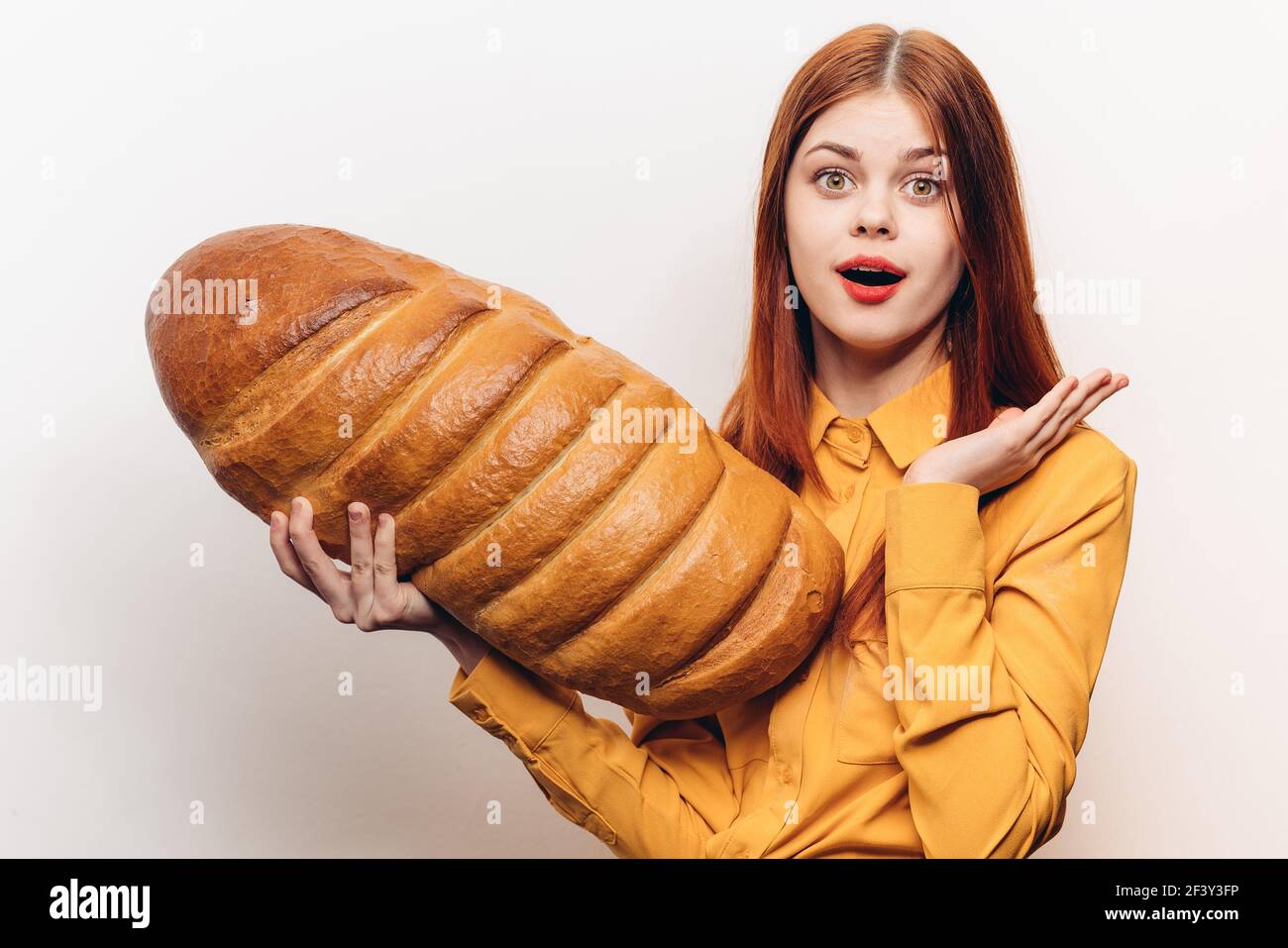 emotional woman holding a loaf in a horizontal position on a light ...