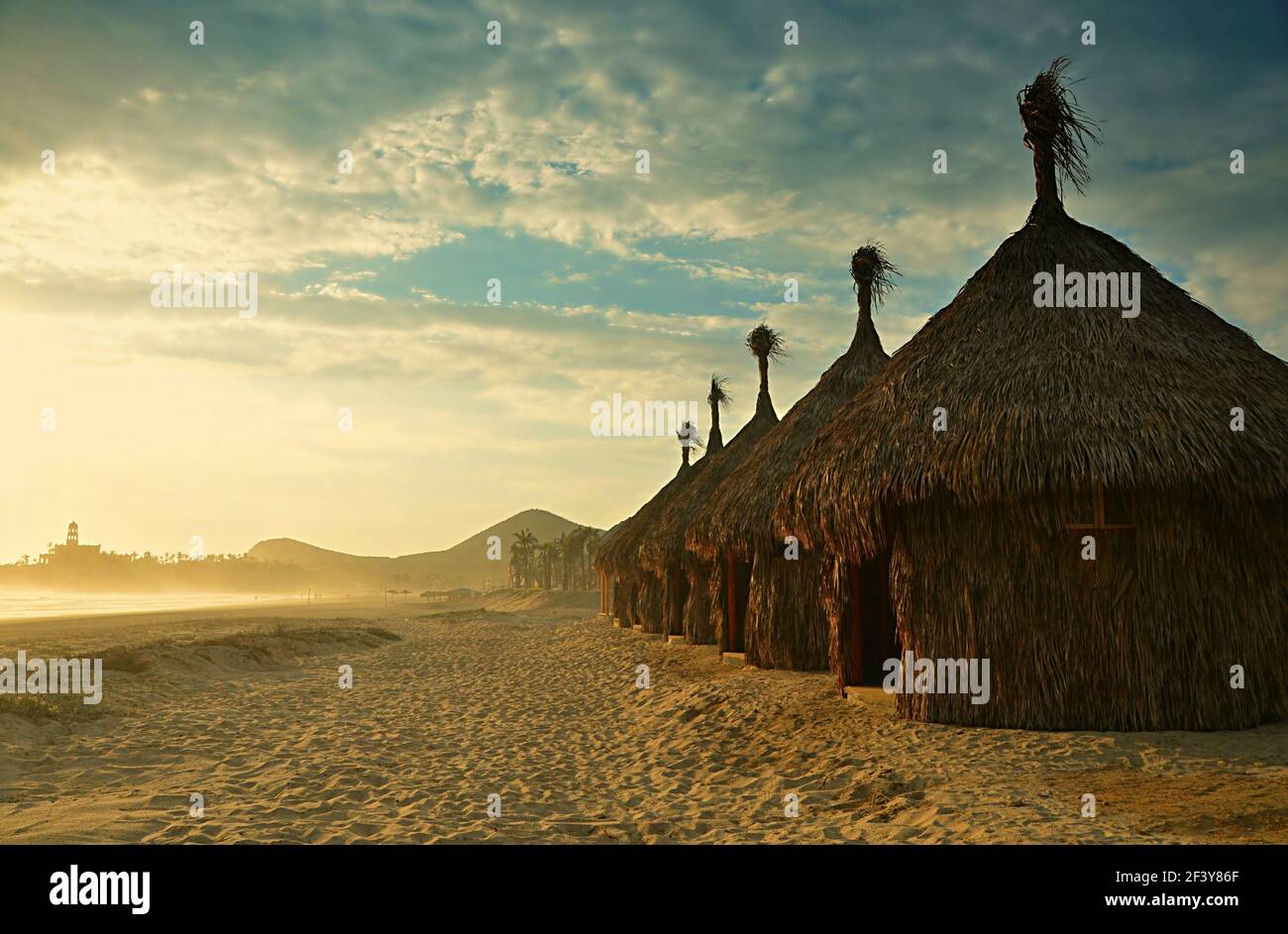 Sunset seascape with thatched roof bungalow huts on the sandy beach of ...