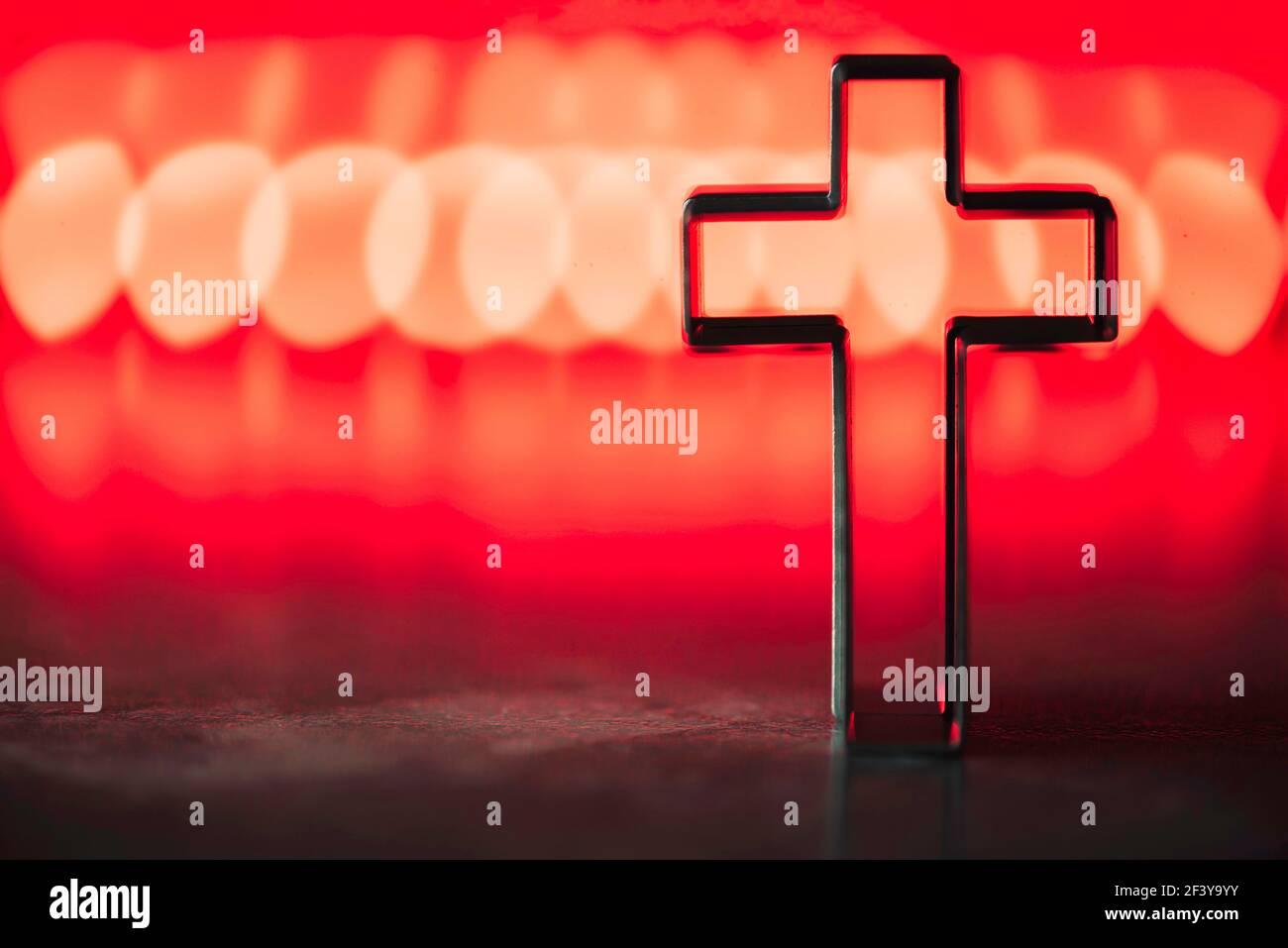 Silhouette of christian cross on red background, soft bokeh lights ...