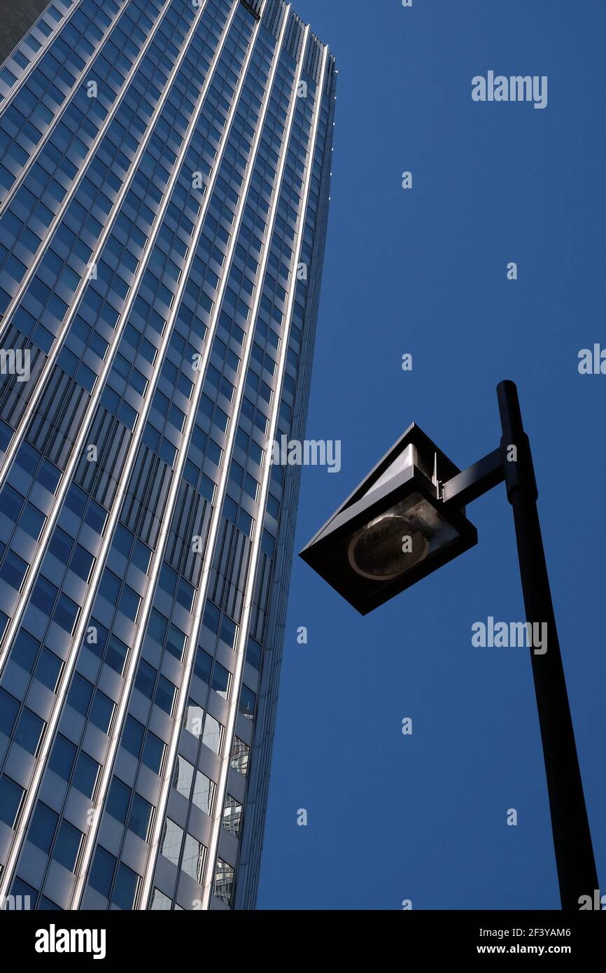 A low angle view of a tall modern building and streetlight lamp post in ...