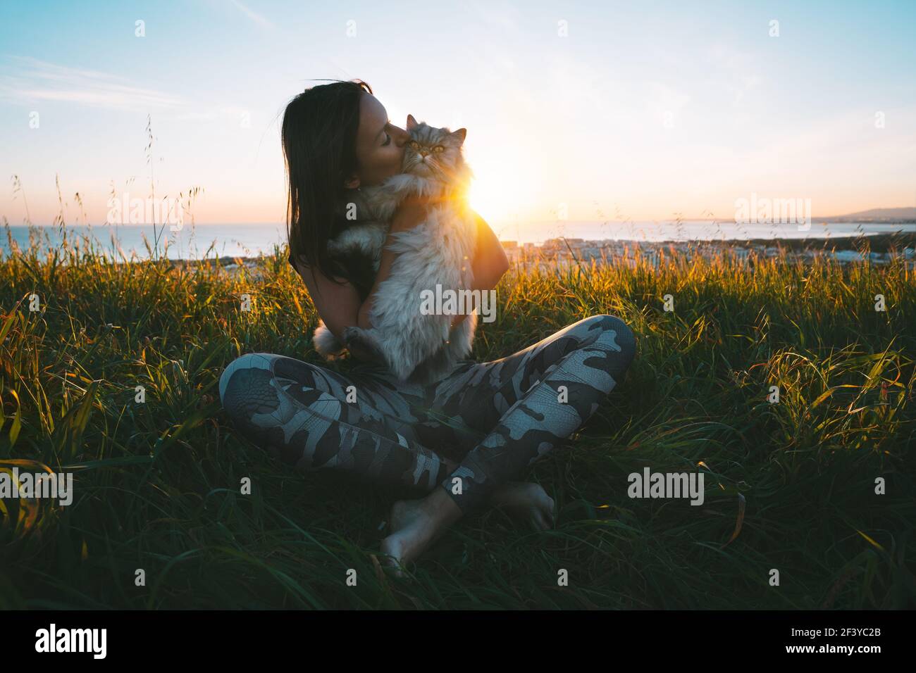 Cute girl kisses her lovely funny beautiful cat outdoors at sunset. Cat ...