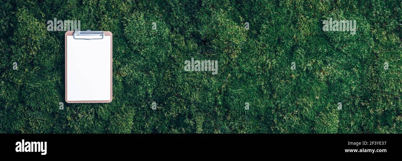 Clipboard, paper, pen on green grass, moss background. Copy space. Top ...