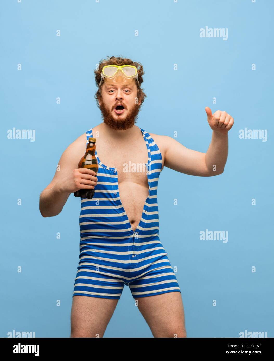 Funny red-headed man in swimming suit with beer isolated on blue ...