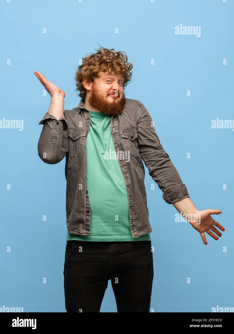 Funny young red-headed man in casual clothes isolated on blue ...