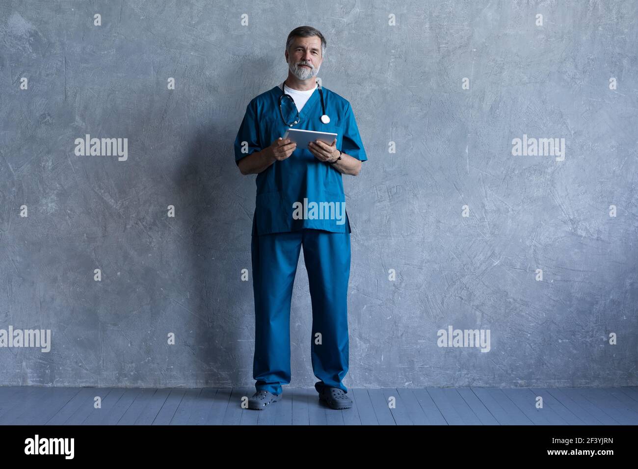 Full-length portrait of professional mature surgeon looking at camera ...