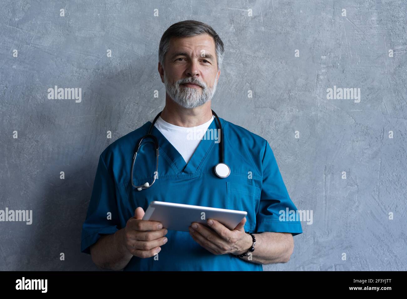 Portrait of professional mature surgeon looking at camera while ...