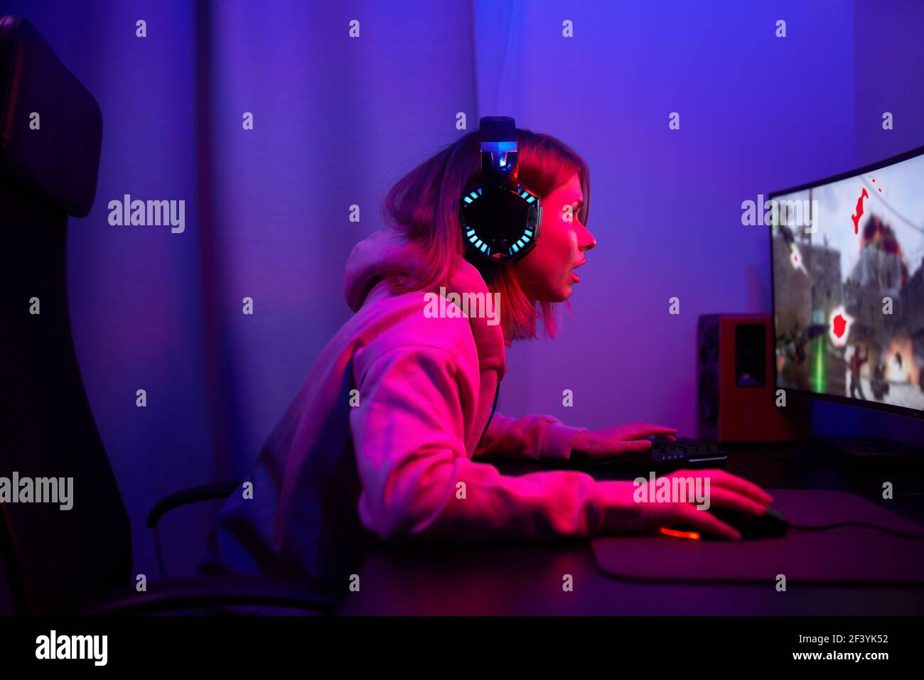 Young gamer girl sitting at pc in neon lights Stock Photo - Alamy