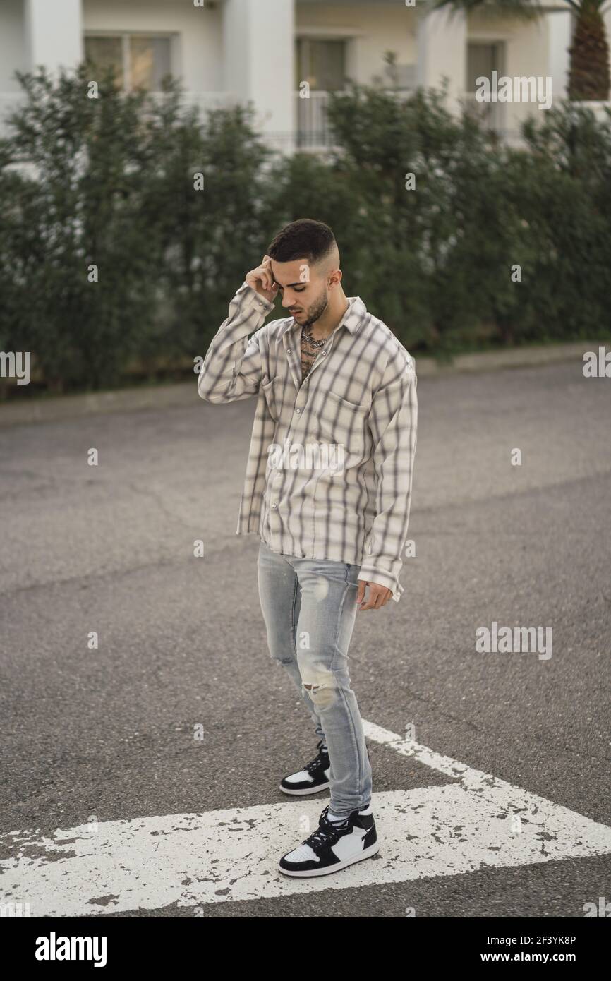 A vertical shot of a handsome Caucasian Spanish man with tattoos posing ...