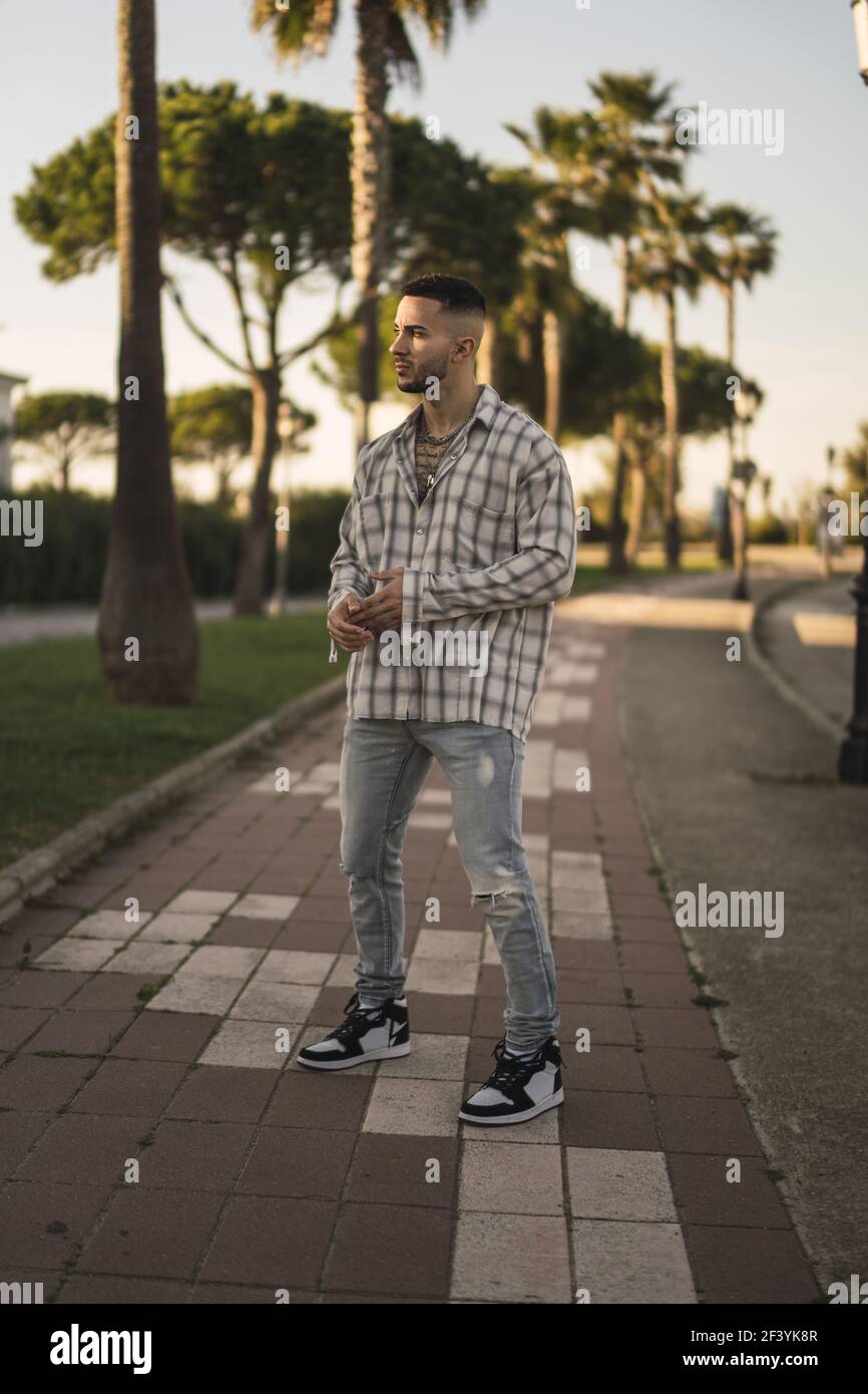 A vertical shot of a handsome Caucasian Spanish man with tattoos posing ...
