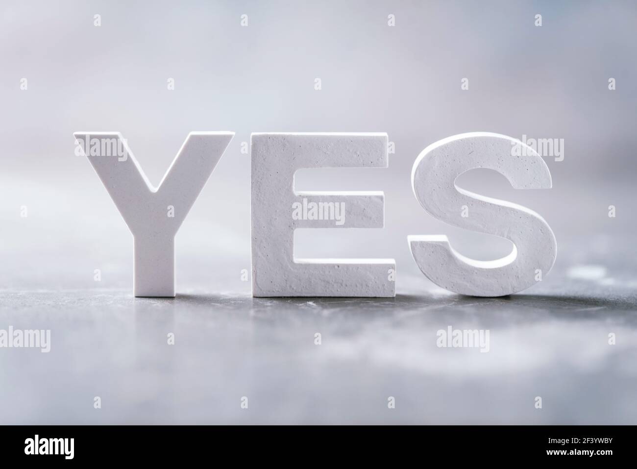 Word YES made with cement letters on grey marble background. Copy space ...