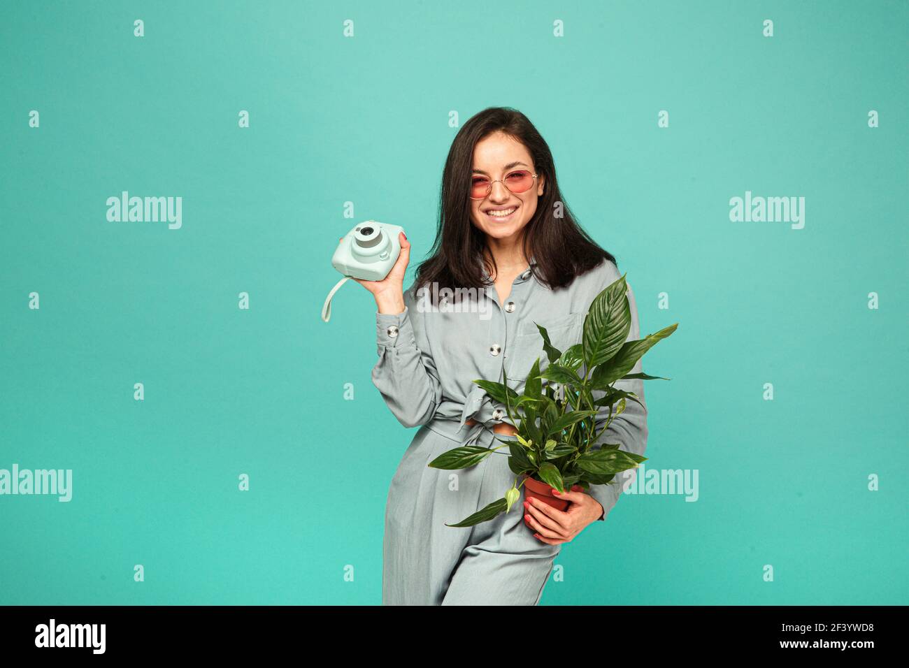 Photo of attractive lady in sunglasses holds camera, plant and has some ...
