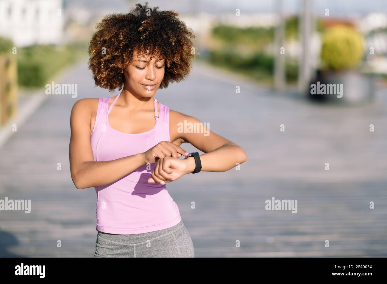 Young black woman using smartwatch touching touchscreen in active ...