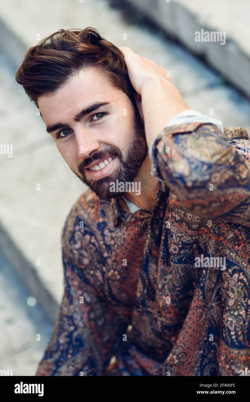 Young smiling man, model of fashion, wearing modern shirt in the street ...