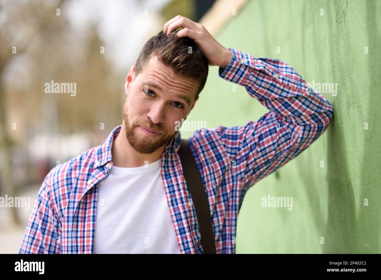 Attractive young man standing in urban background. Lifestyle con ...