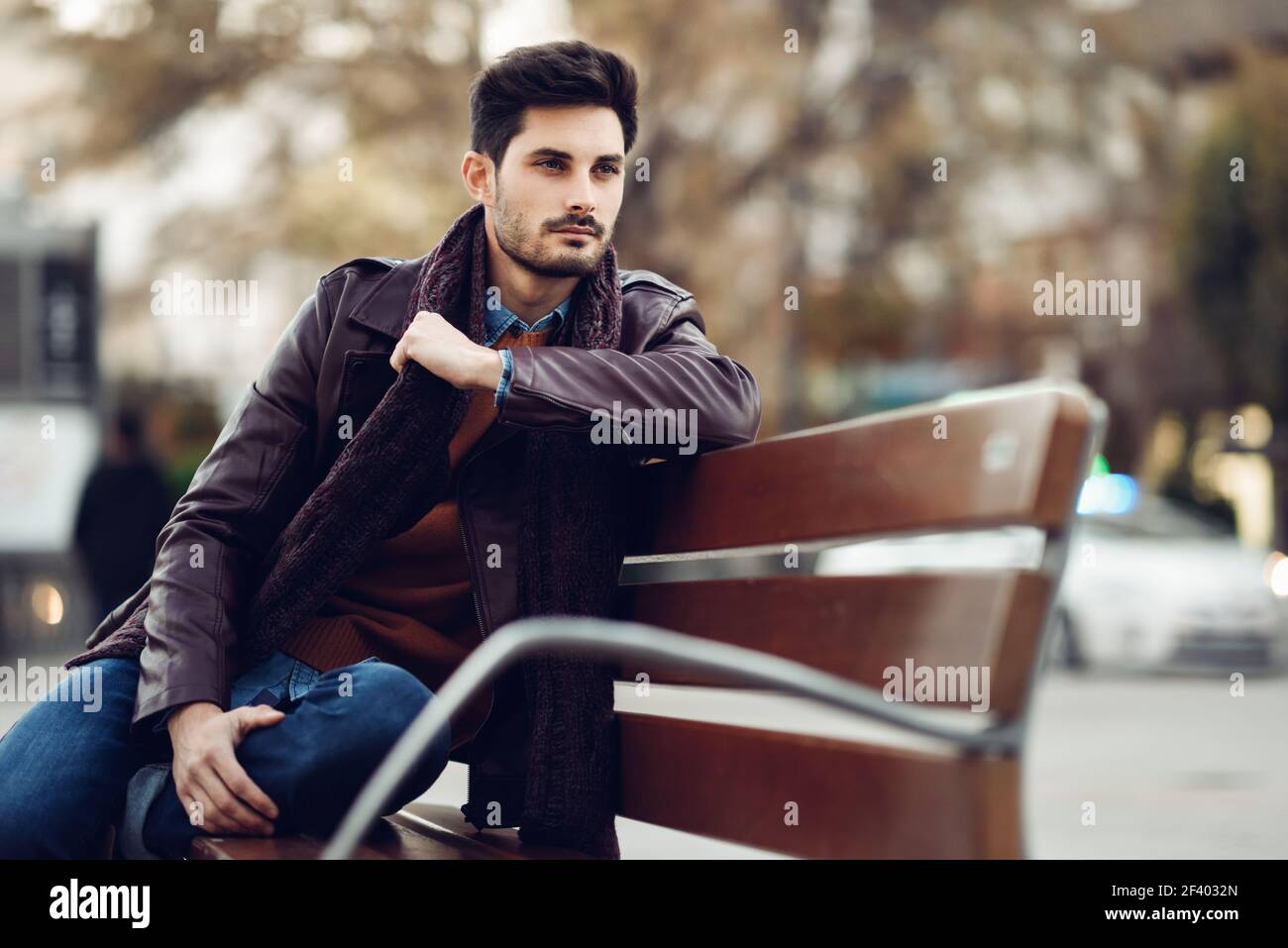 Thoughtful young man sitting on an urban bench. Attractive guy with ...