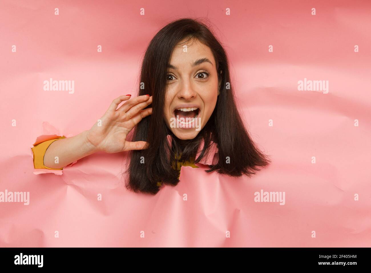 Concept photo of young female tearing paper and peeking out hole ...