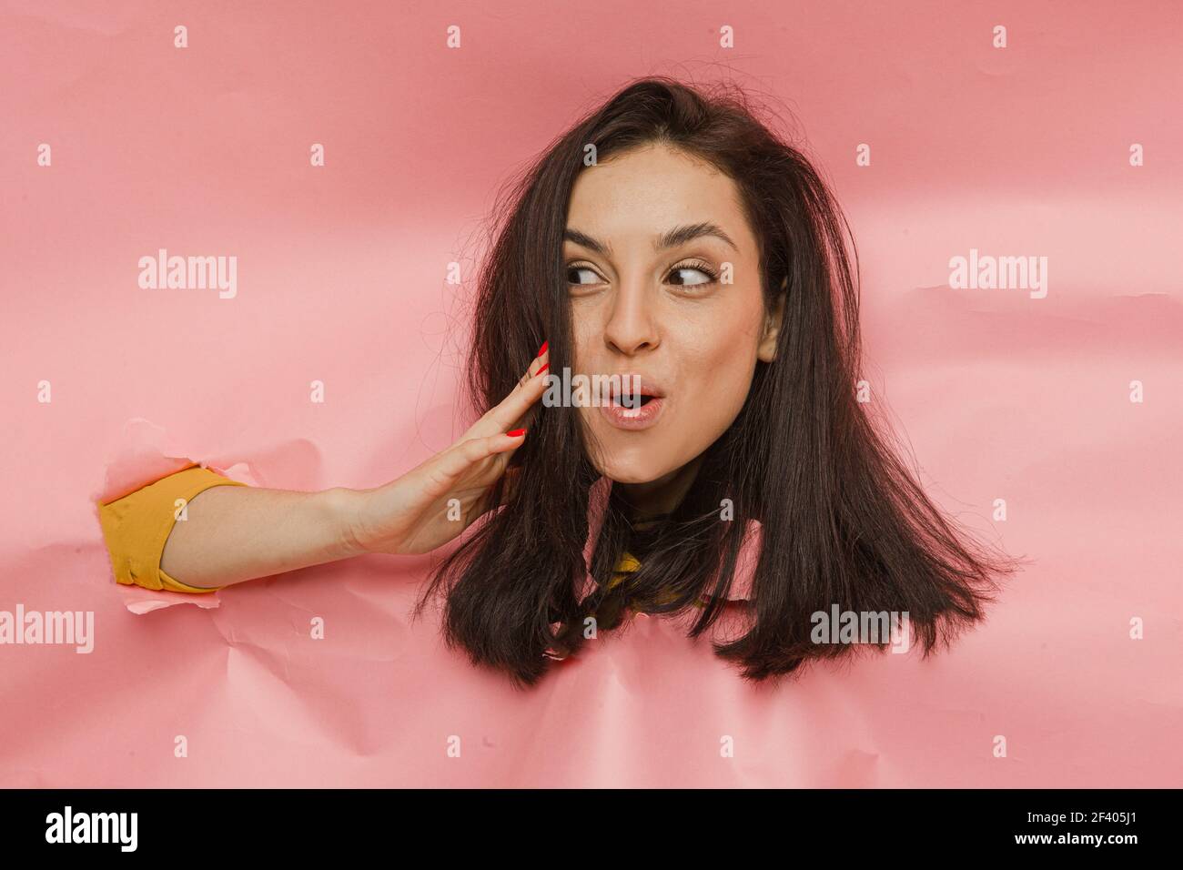 Concept photo of young female tearing paper and peeking out hole ...