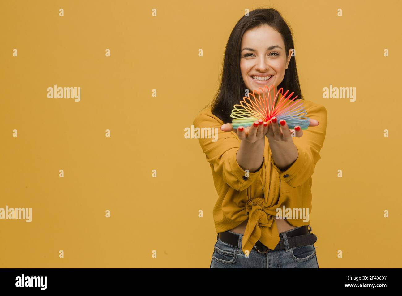 Photo of cute female with nice smile holds slinky. Wears yellow shirt ...