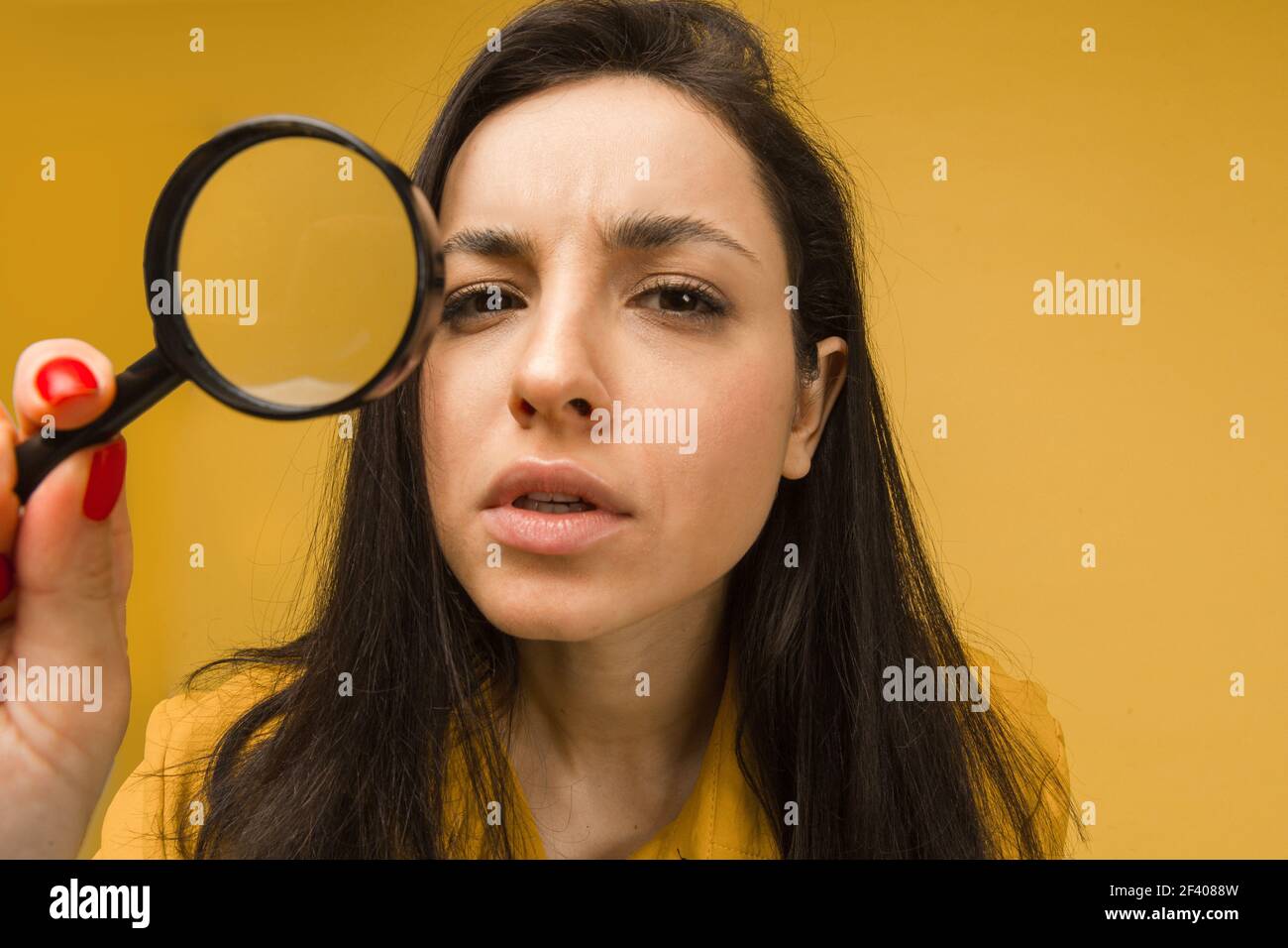 Photo of cute female holds magnifying glass and looking for something ...