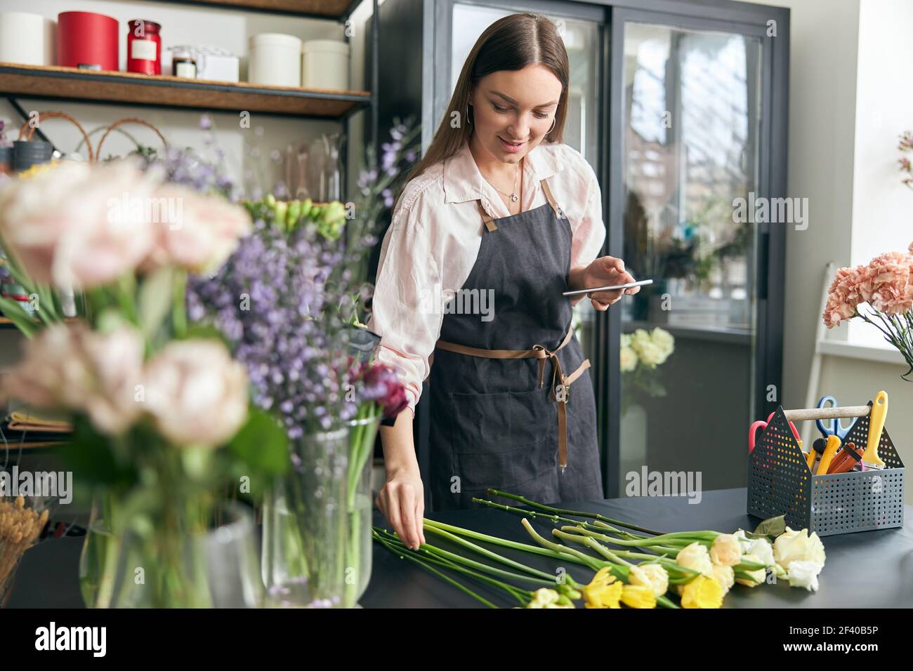 Photo of successful modern florist wearing apron, creating beautiful ...