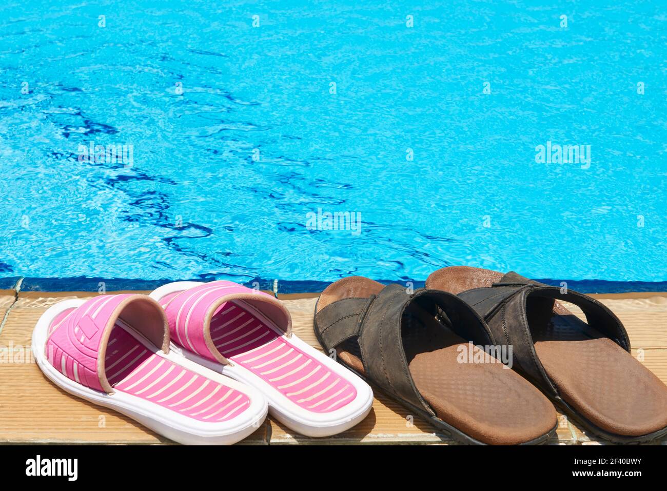 A pair of mens and womans sandals by side of swimming pool Stock Photo ...
